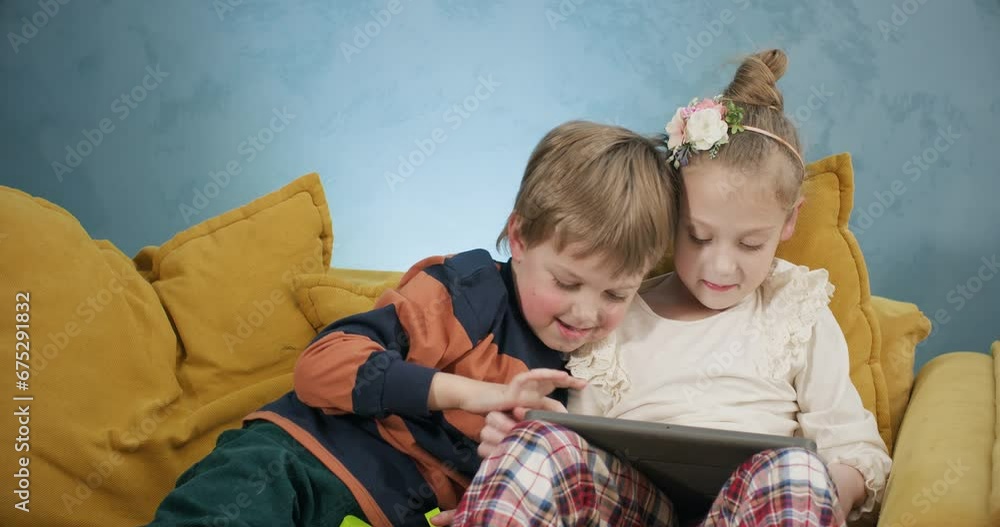 Preschooler brother and elder sister sit on couch watching funny ...
