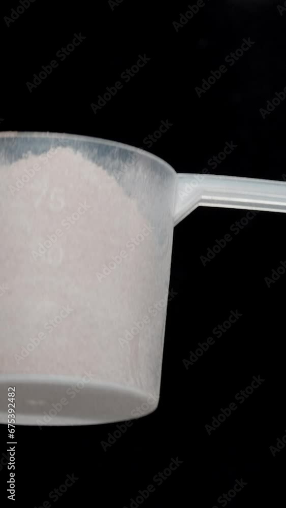 Vertical video. Top view on a black background as I sprinkle protein ...