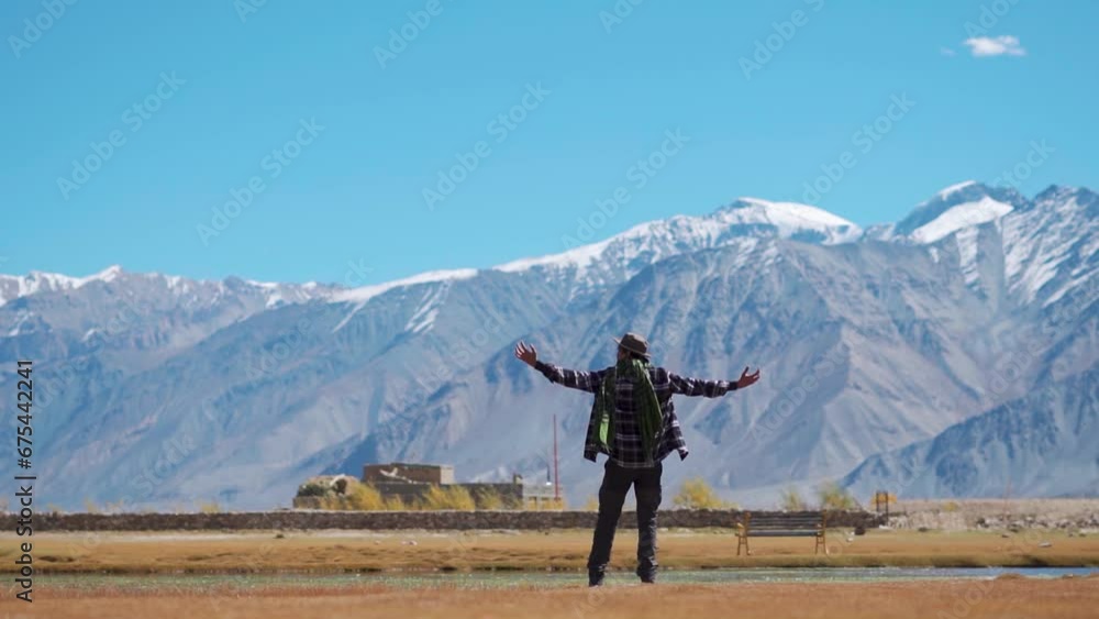Rear View shot of an Indian man wearing hat raising his arms in front ...