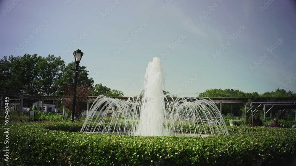 a small water fountain with lights behind it next to the trees Stock ...