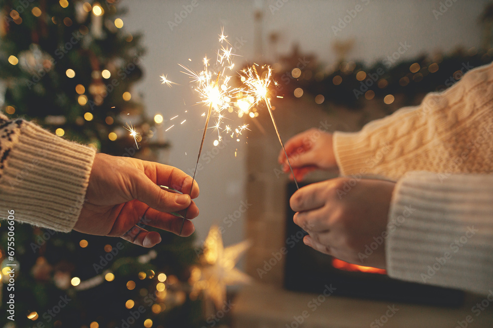 Hands holding burning fireworks against modern fireplace and christmas ...