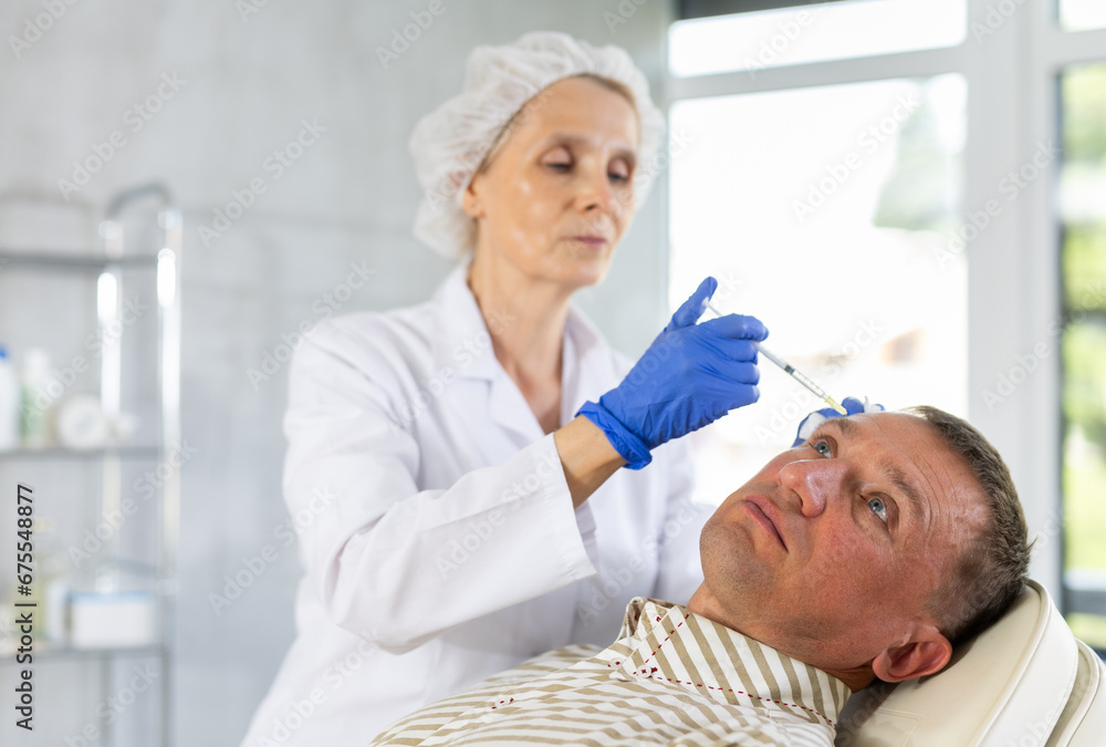 Concentrated professional female cosmetologist performing face skin ...