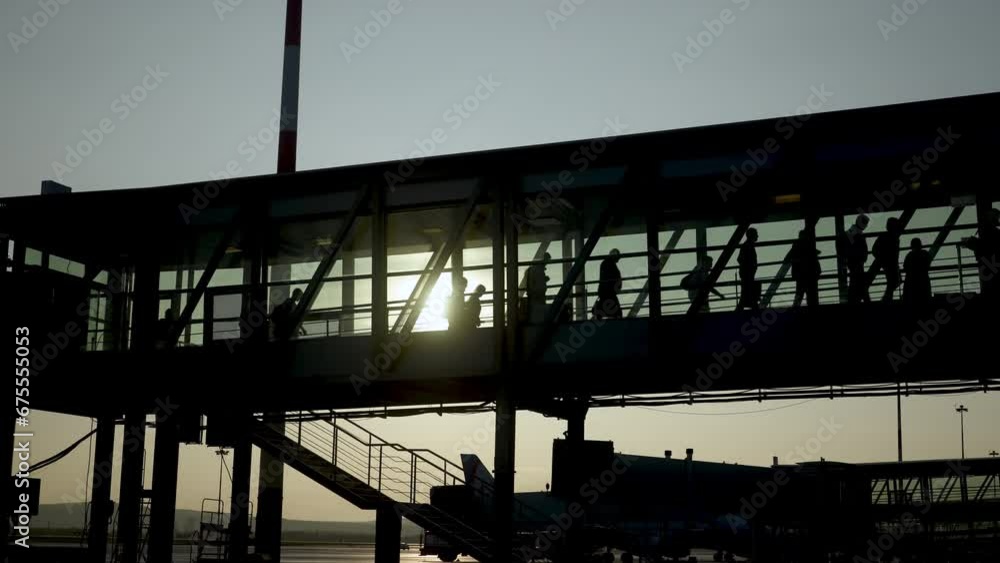Passengers boarding using an air bridge. People walk in silhouette ...