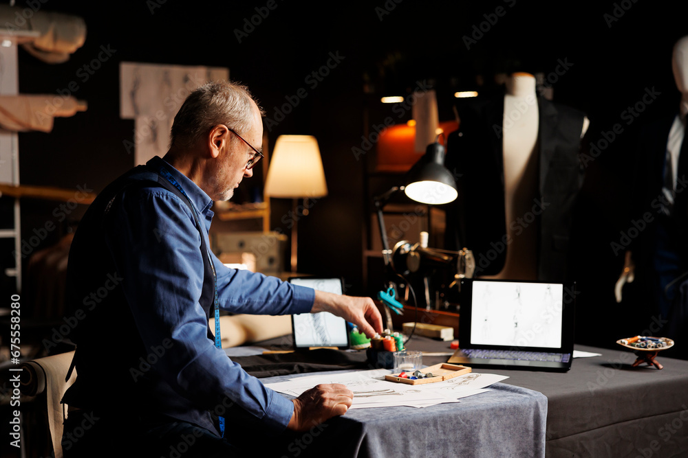 Elderly fashion designer preparing his atelier shop workspace before ...