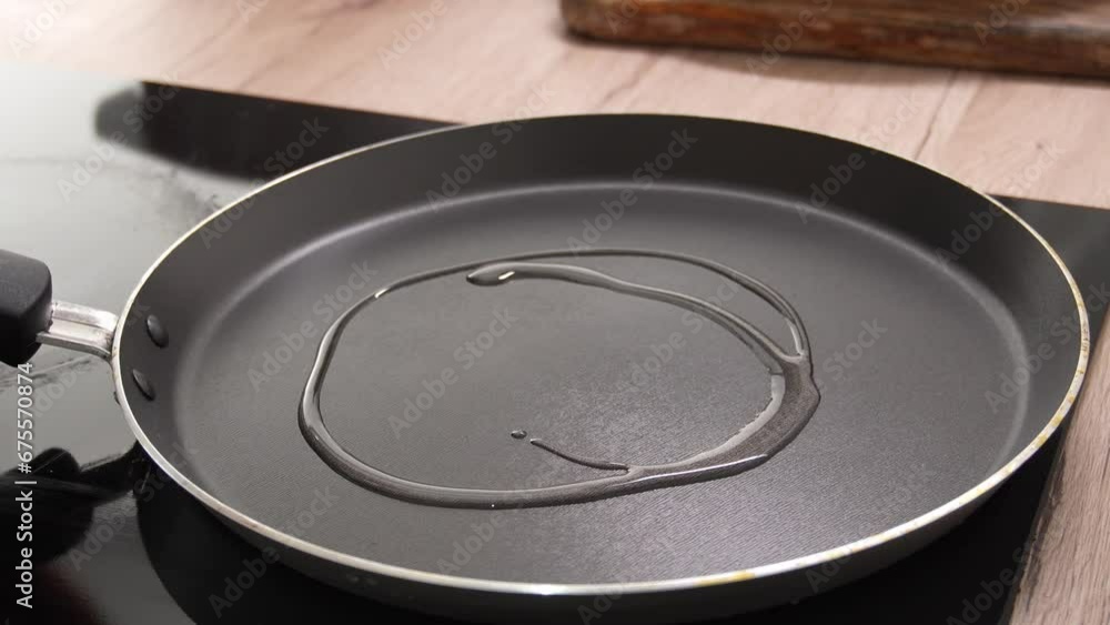 Pouring oil into frying pan. A close-up view captures the moment oil is ...