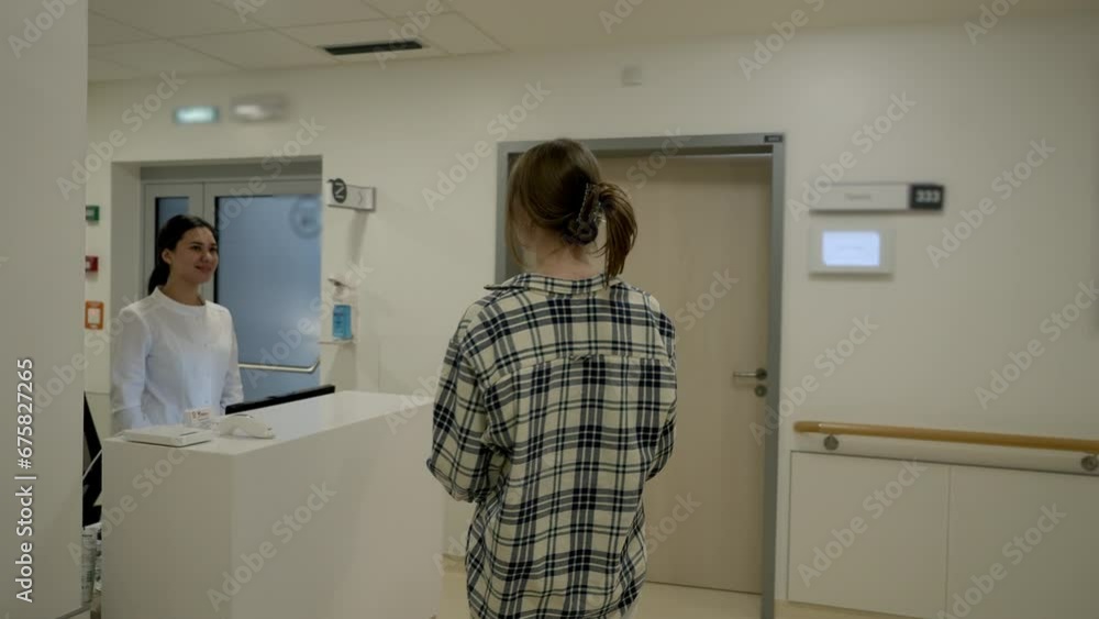 Patient coming towards the reception desk at a hospital. Speaking with ...