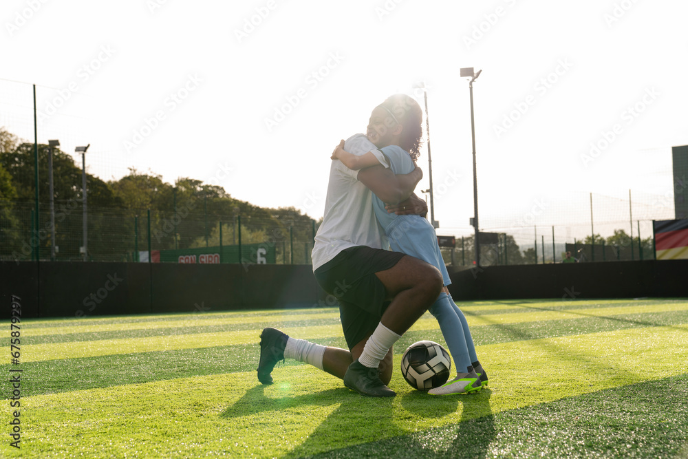 Coach and girl (6-7) hugging on soccer field Stock Photo | Adobe Stock