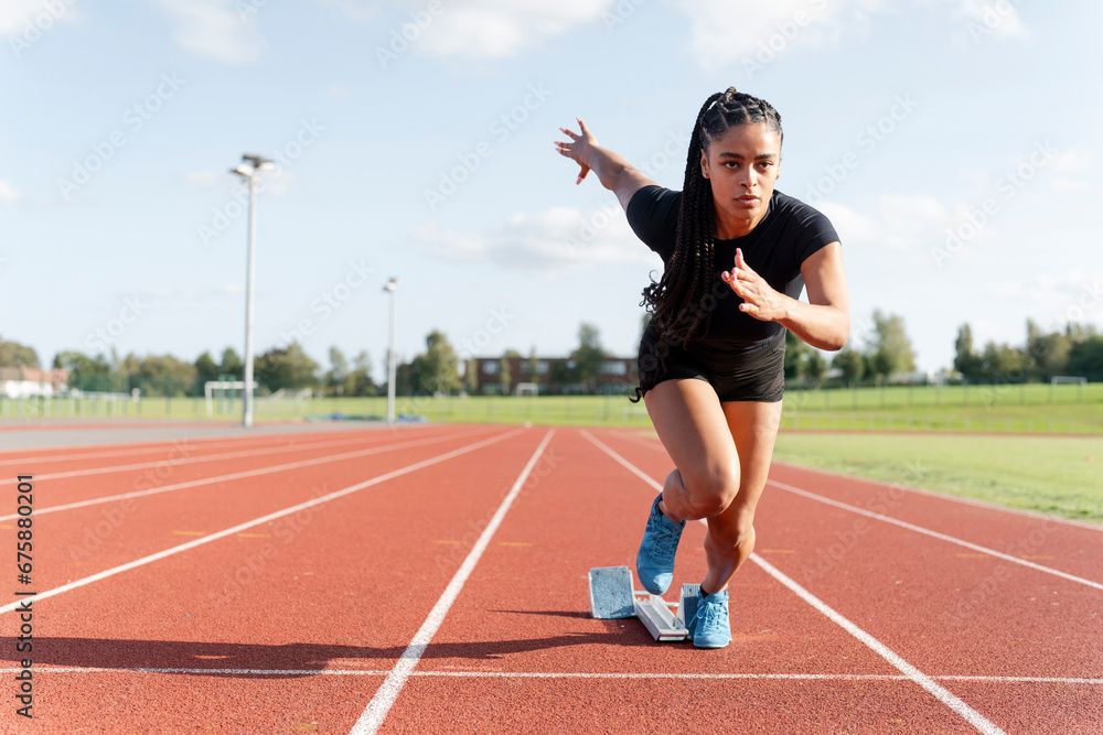 Female athlete sprinting off starting line at stadium Stock Photo ...