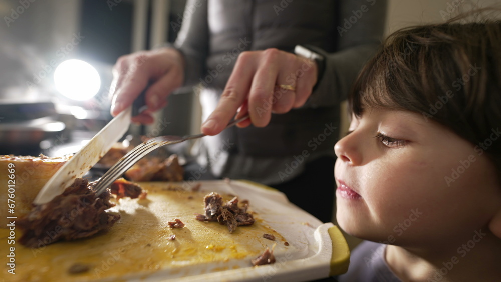 Little boy grabbing food by kitchen counter while mother prepare meal ...