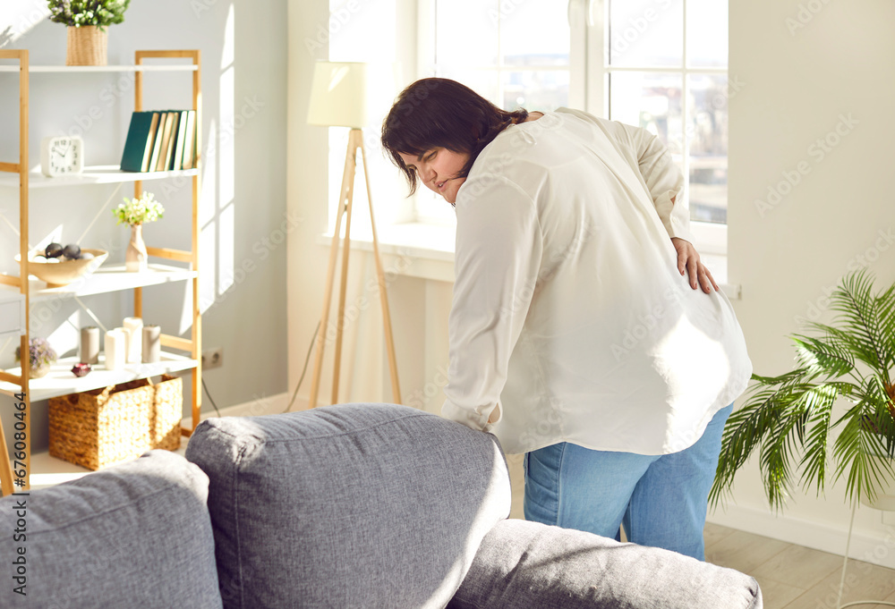 Overweight young woman suffering from chronic back pain backache. Plus ...