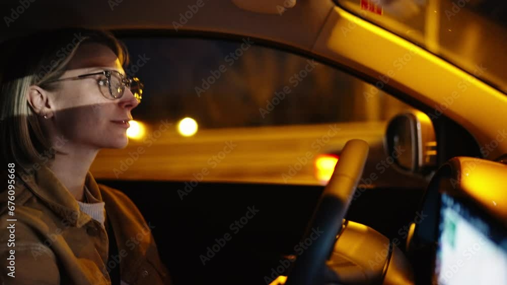 Side view of focused Caucasian woman driving electric vehicle at night ...