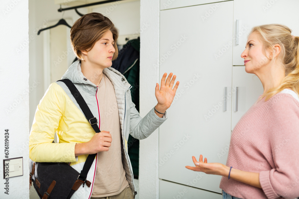 Teenage boy saying goodbye to mother at doorway as he leave home for ...