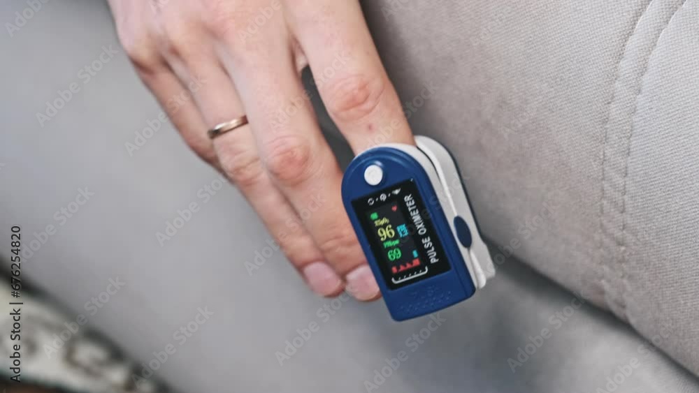 Man measures pulse and oxygen saturation with a pulse oximeter at home ...