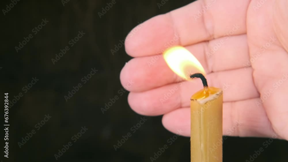 Close-up candle in dark, female hands shield burning flame from wind ...
