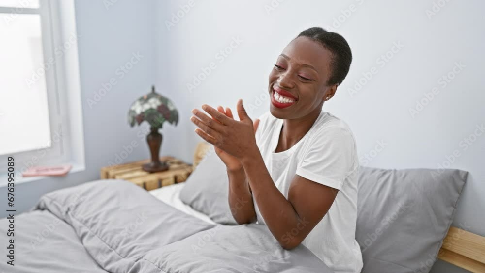 Beaming african american woman lying on bed clapping hands together in ...