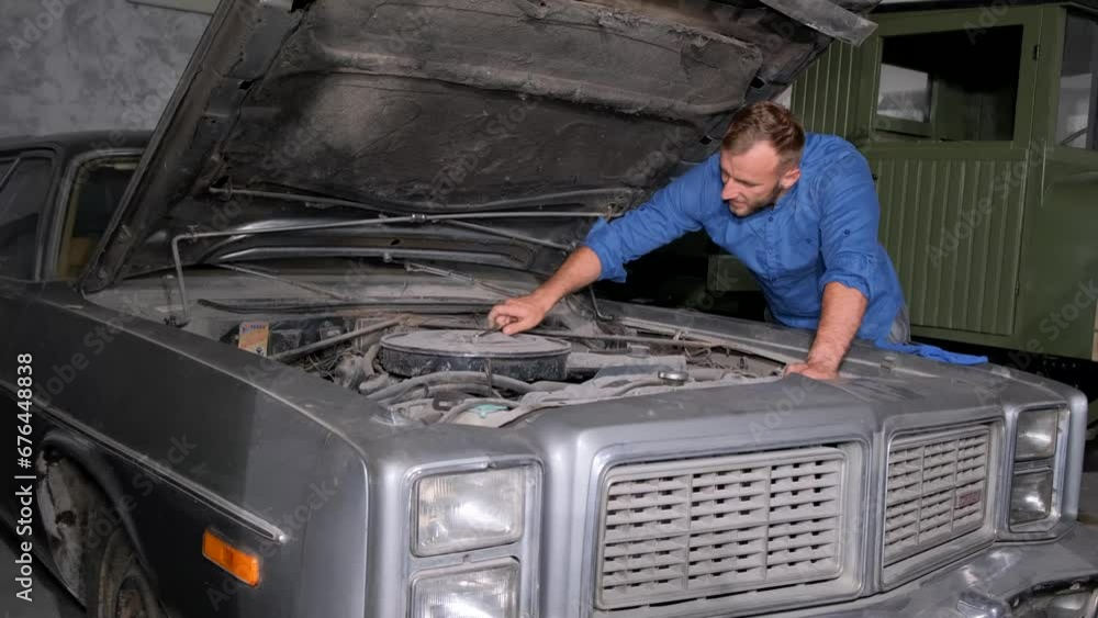 A car mechanic examines the engine of a retro car. Repair of old cars ...