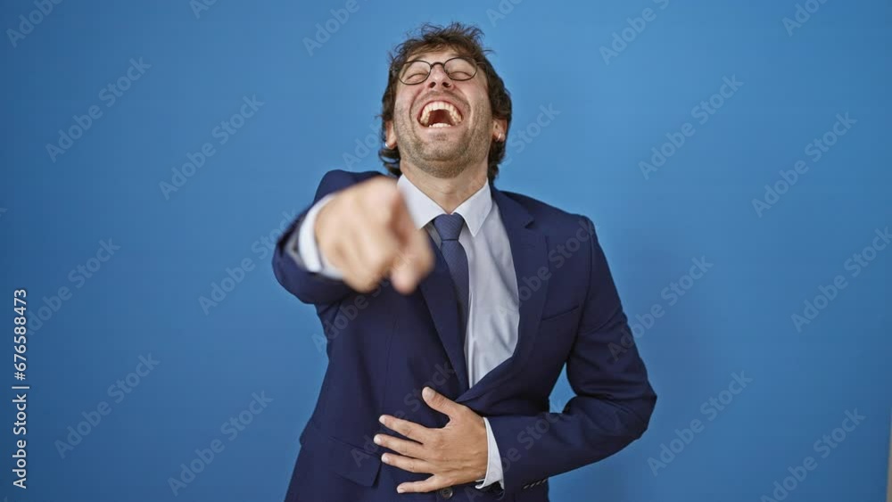 Young blonde guy in business suit has a laugh on you, pointing finger ...