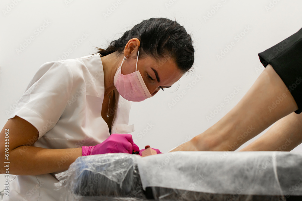 Pedicure master in medicine mask painting nails of foot with red ...