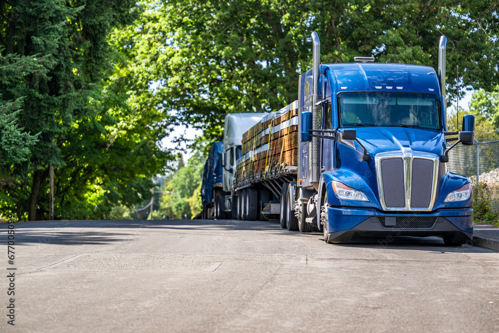 Loaded big rig semi trucks with flat bed semi trailers standing on the ...