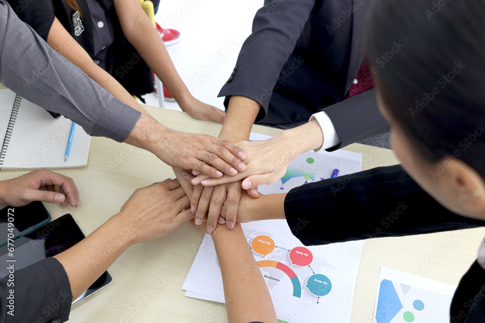 Overhead view of businesspeople join hands together over meeting desk ...