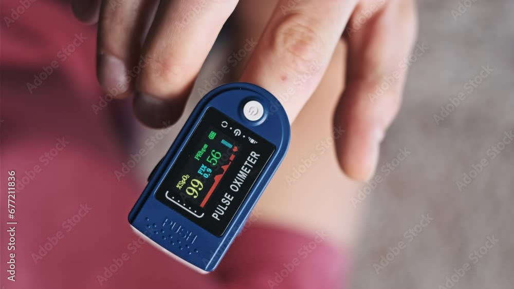 Man measures pulse and oxygen saturation with a pulse oximeter at home ...