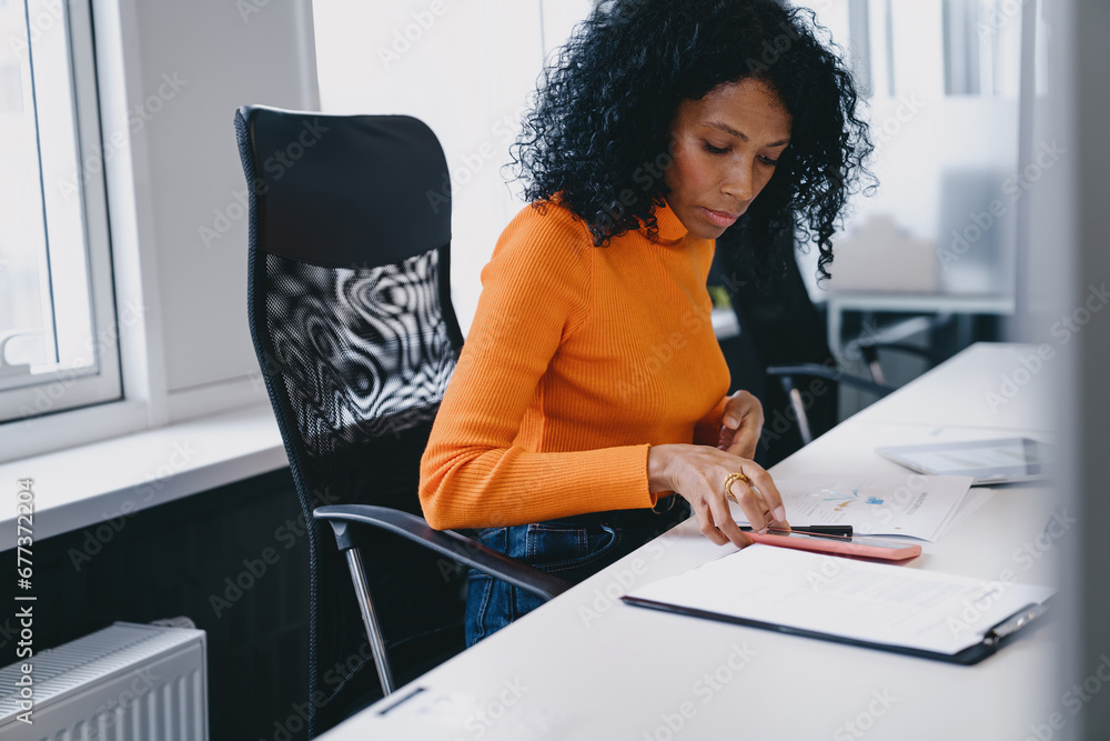 Diligent Black female accountant in her 30s, managing ledgers in a ...