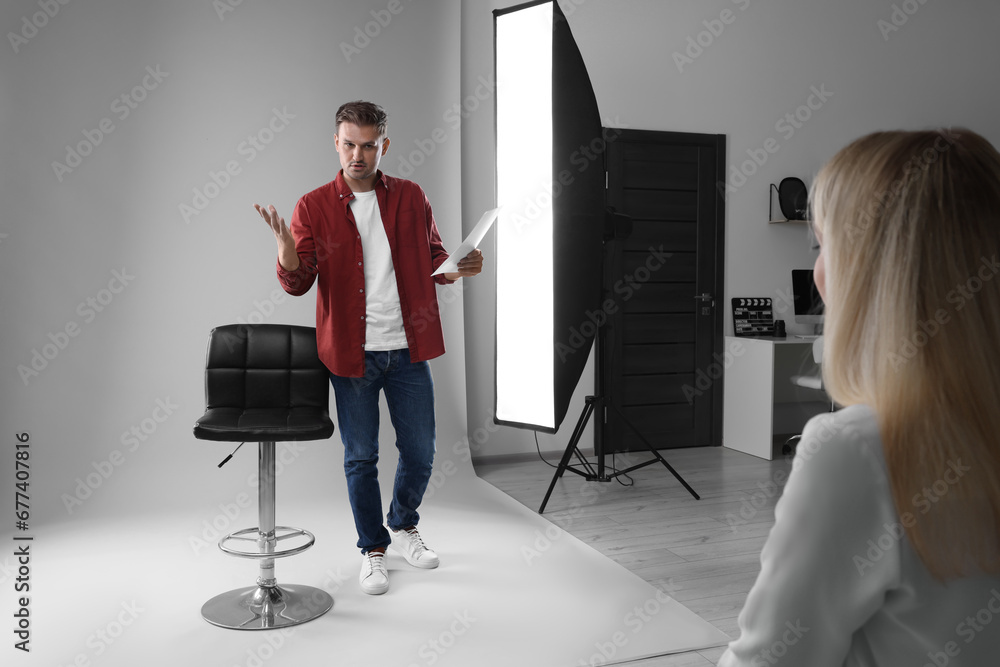 Man with script performing in front of casting director against light ...