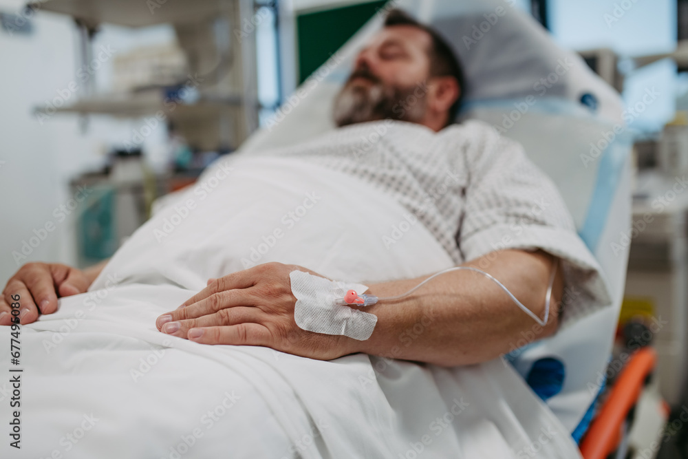 Patient with IV cannula in vein, hand lying in hospital bed. Man in ...