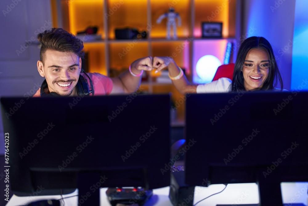 Man and woman streamer playing video game bump fists at gaming room ...