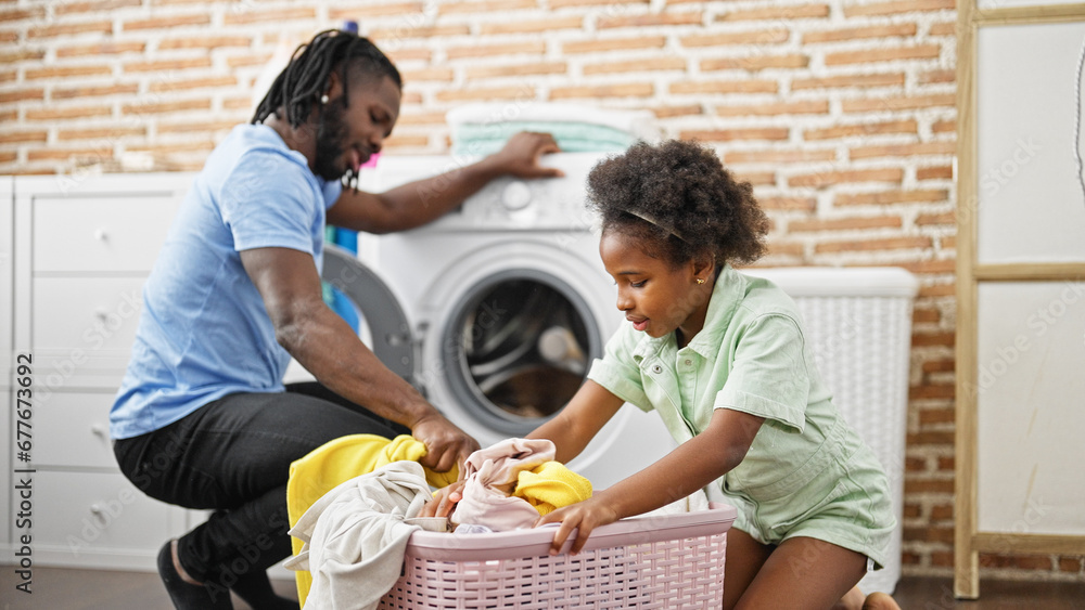 African american father and daughter washing clothes at laundry room ...