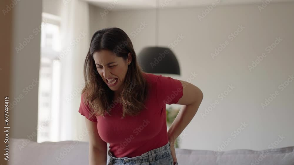 Caucasian woman standing up from a couch at home experiences sudden ...