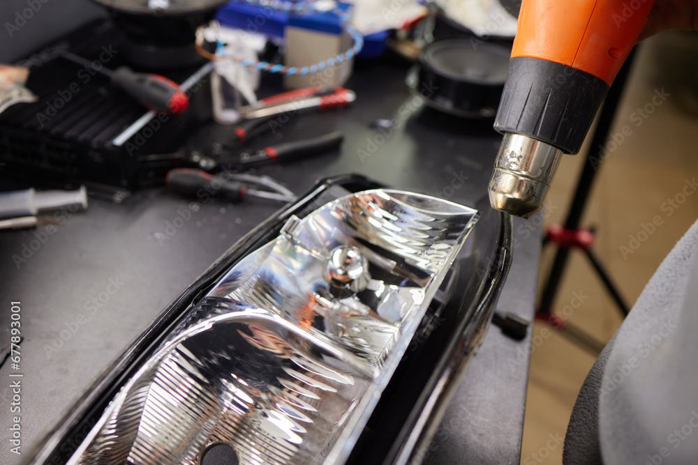 Car headlight in repair close-up. The car mechanic installs the lens in ...