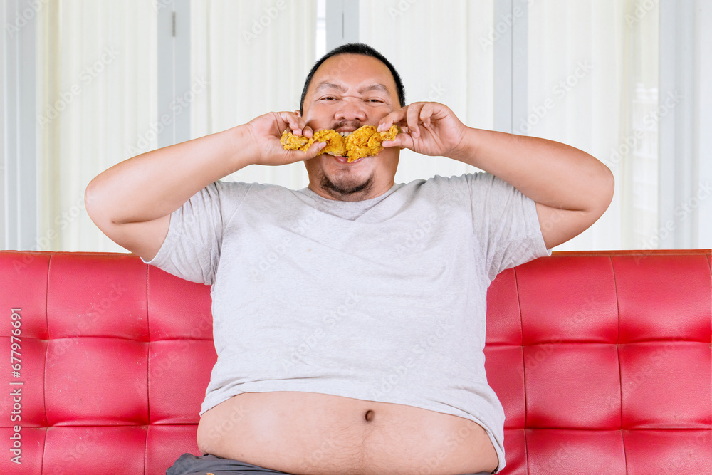 Foto de Greedy overweight man eating fried chicken - junk food while ...
