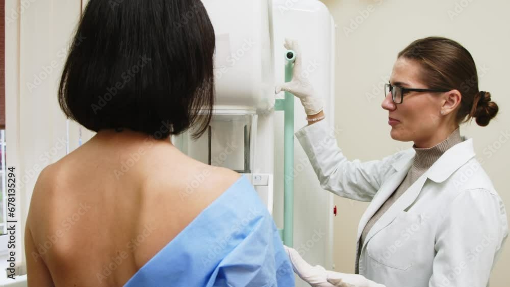 A female doctor in a modern clinic explains the mammography procedure ...