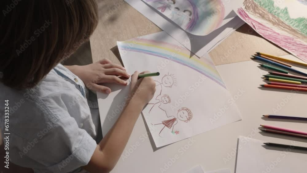 Creative little boy drawing his family on paper. This artwork captures ...