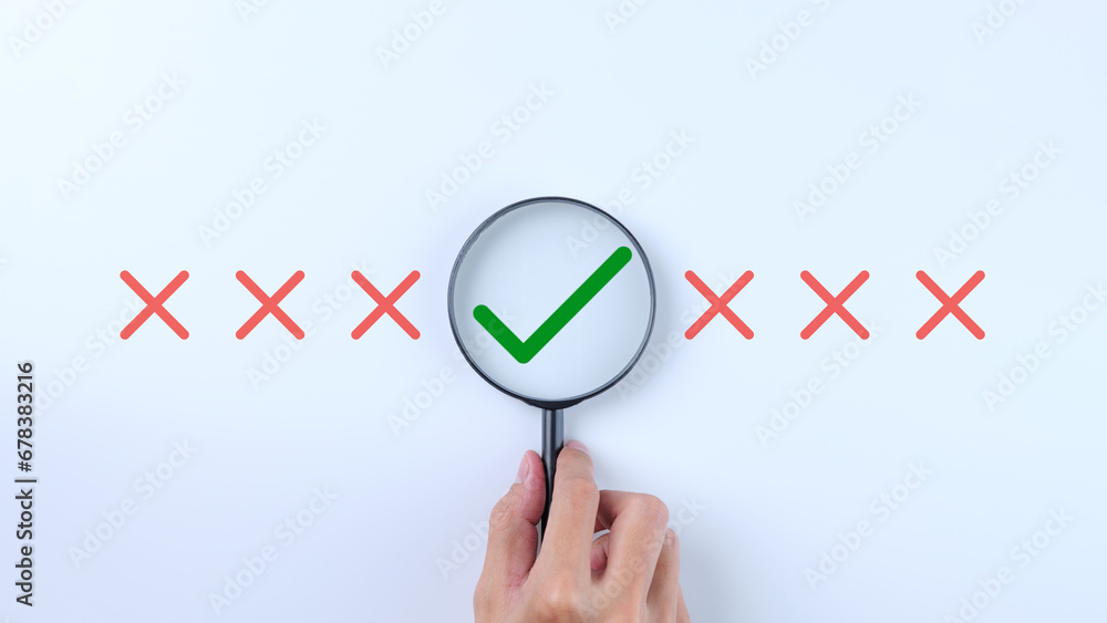 Hand holding a magnifying glass to magnify the check mark. Correct sign ...