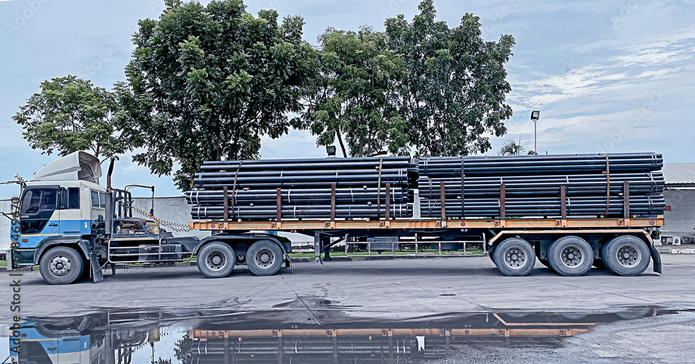 Trucks with long trailers carrying steel bars for building construction ...