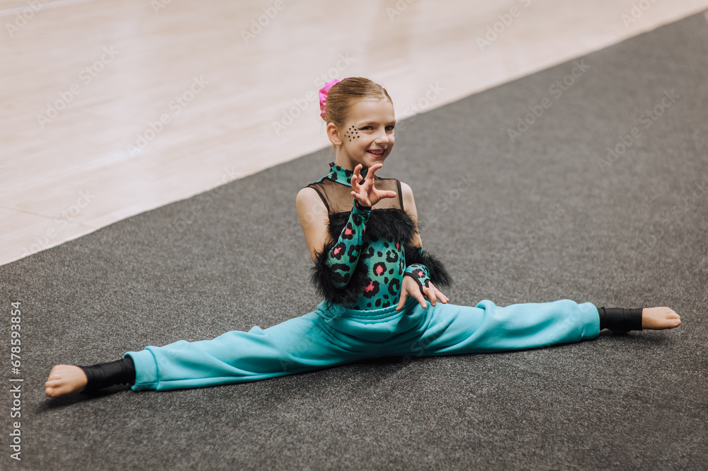 Happy girl athlete in a blue cat tracksuit, an 8-year-old child makes ...
