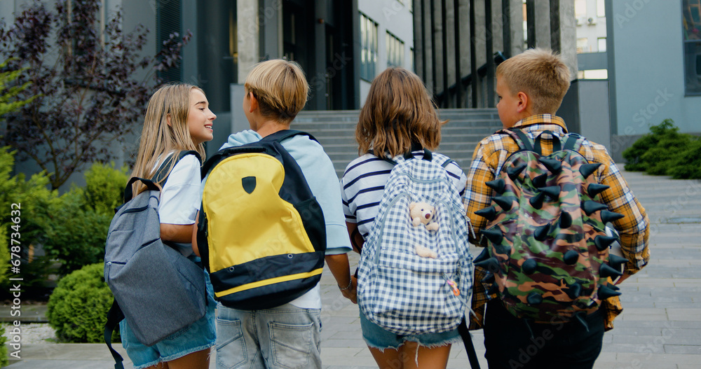 Group of four smart diverse classmates with colorful backpacks are ...