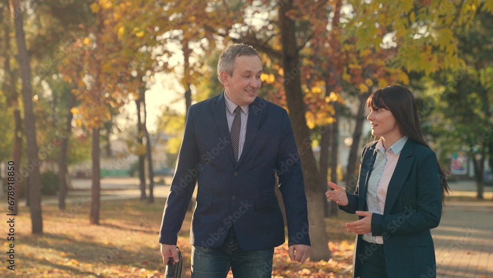 Business partners stroll through autumn park at sun light. Teamwork of ...