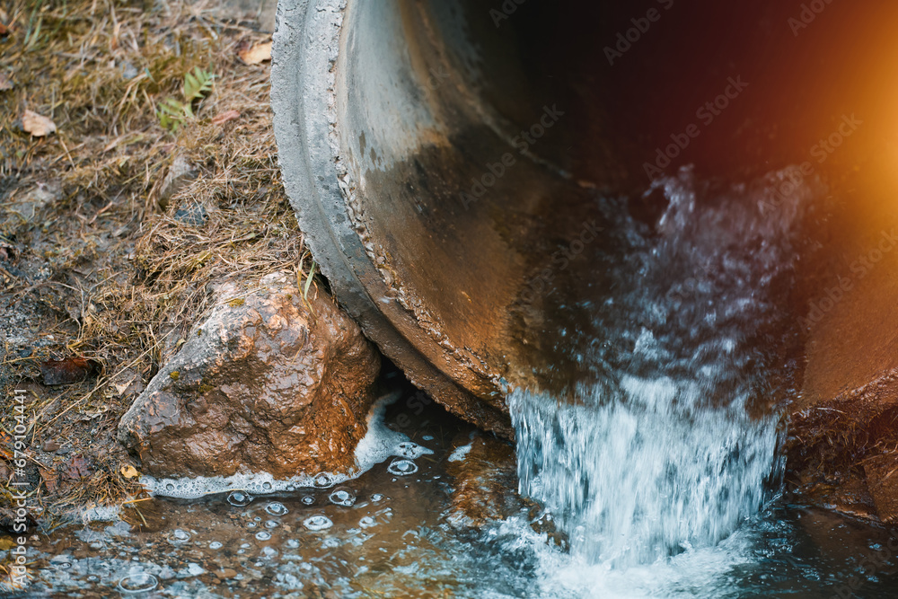 Wastewater and sewage flow from a pipe into a polluted river, creating ...