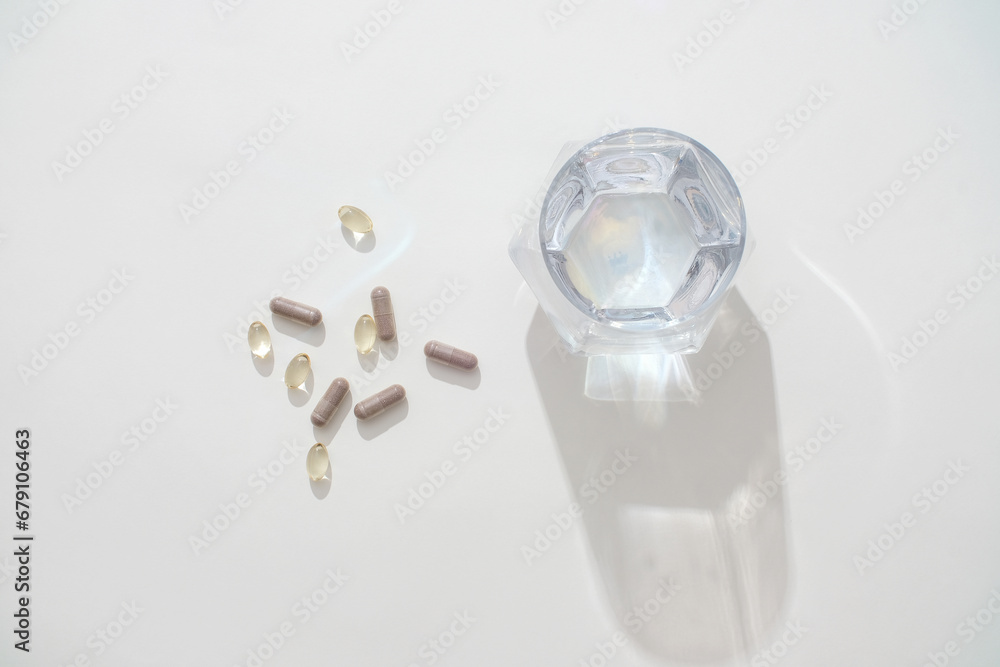 A glass of water on a white background with capsules. Capsule medicine ...