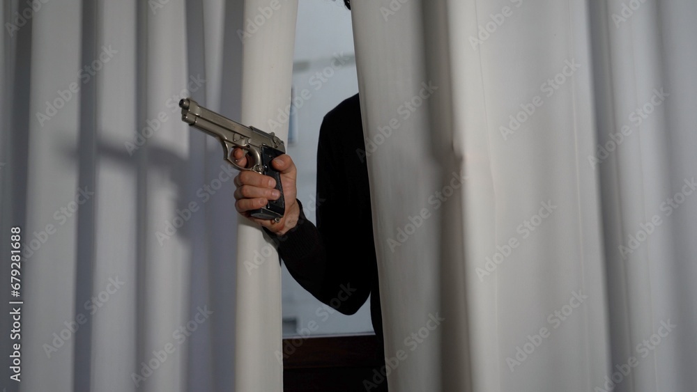thief enters the apartment house with a revolver gun pistol in his hand ...