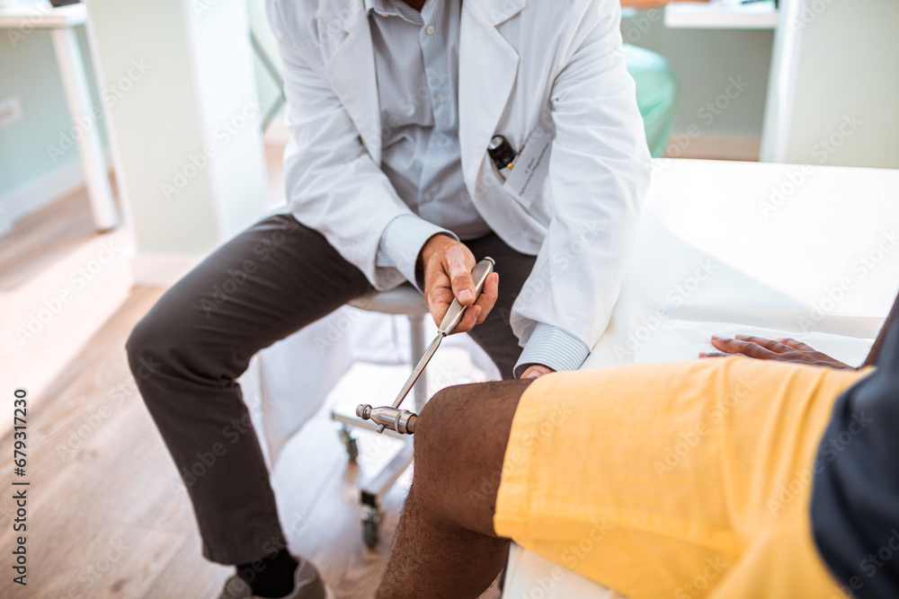 Doctor using a reflex hammer on his patient in the doctors office Stock ...