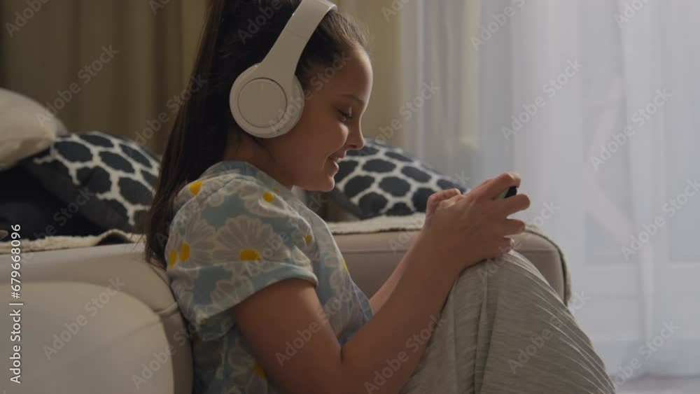 Generation Z girl sitting on floor of living room playing video games ...