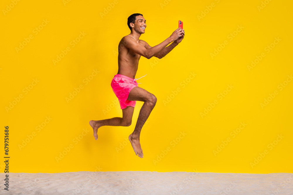 Full length photo of pretty positive shirtless man jumping high texting ...
