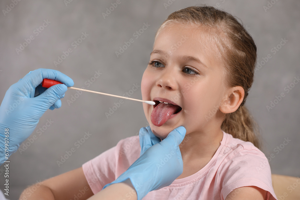 Doctor taking throat swab sample from girl`s oral cavity on grey ...