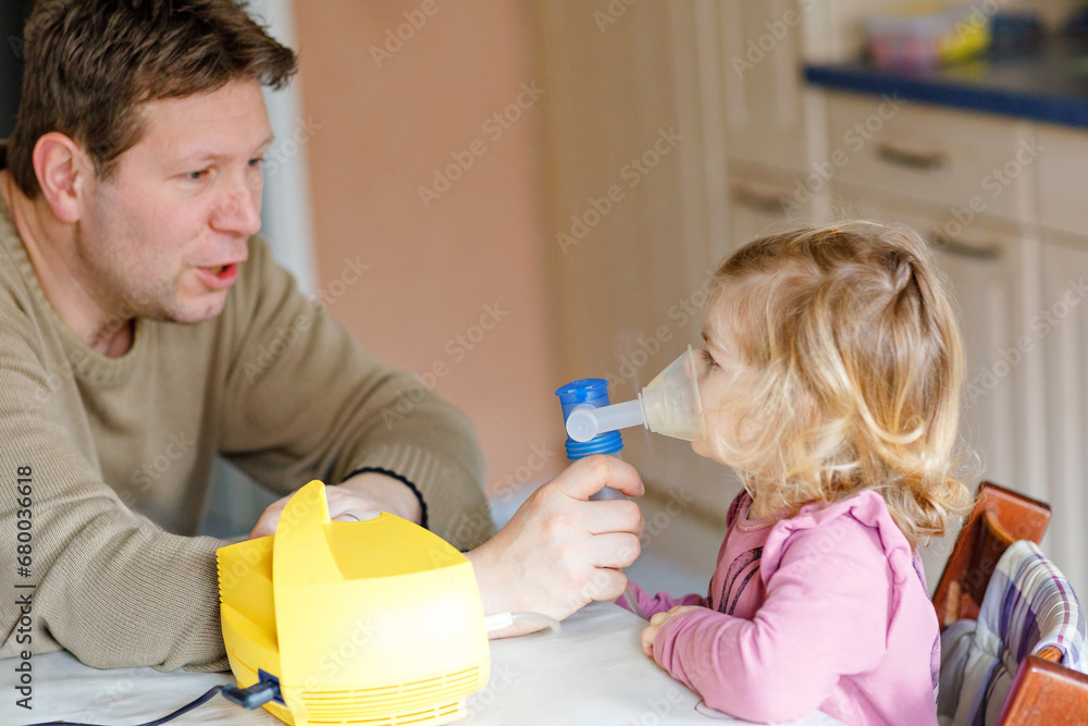 Little toddler girl making inhalation with nebulizer at home. Father ...