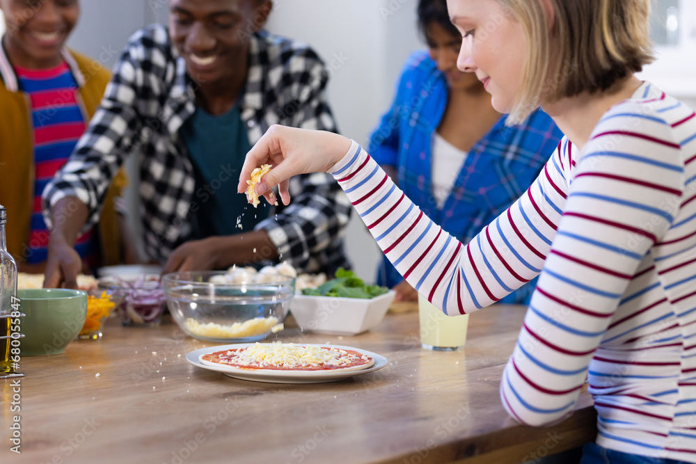 Happy diverse group of teenage friends cooking and making pizza in ...