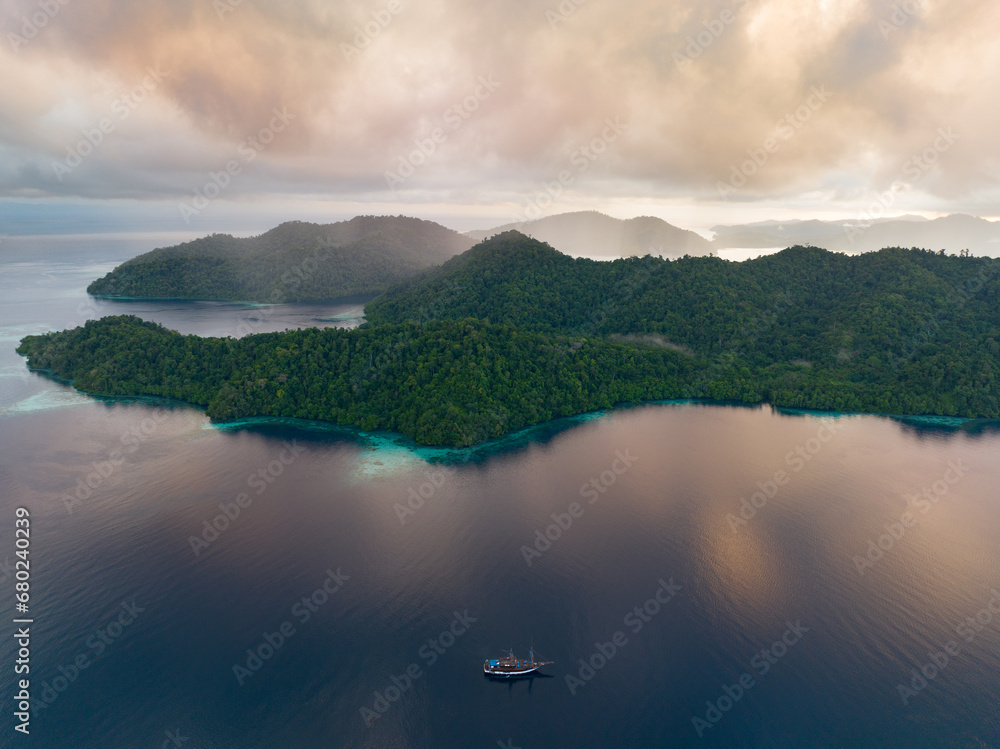 Low, sunlit clouds drift across the island of Batanta in Raja Ampat ...